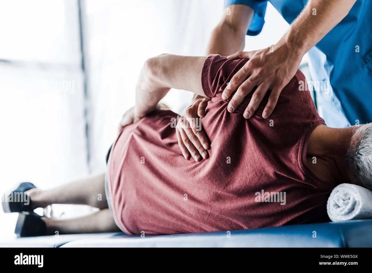 selective focus of doctor touching middle aged patient on massage table ...