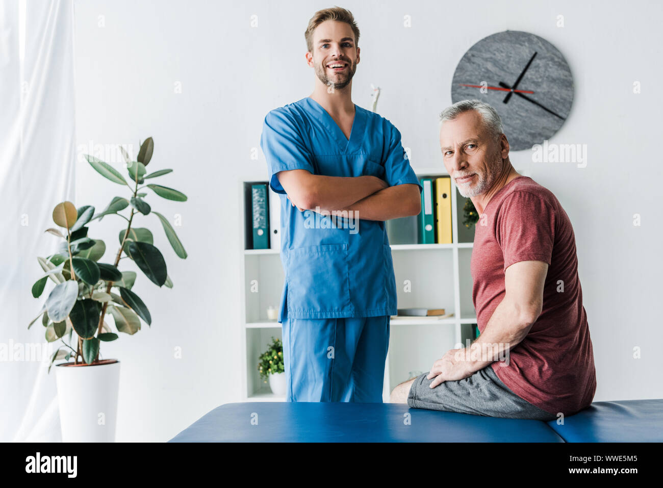 handsome doctor standing with crossed arms near happy patient Stock ...