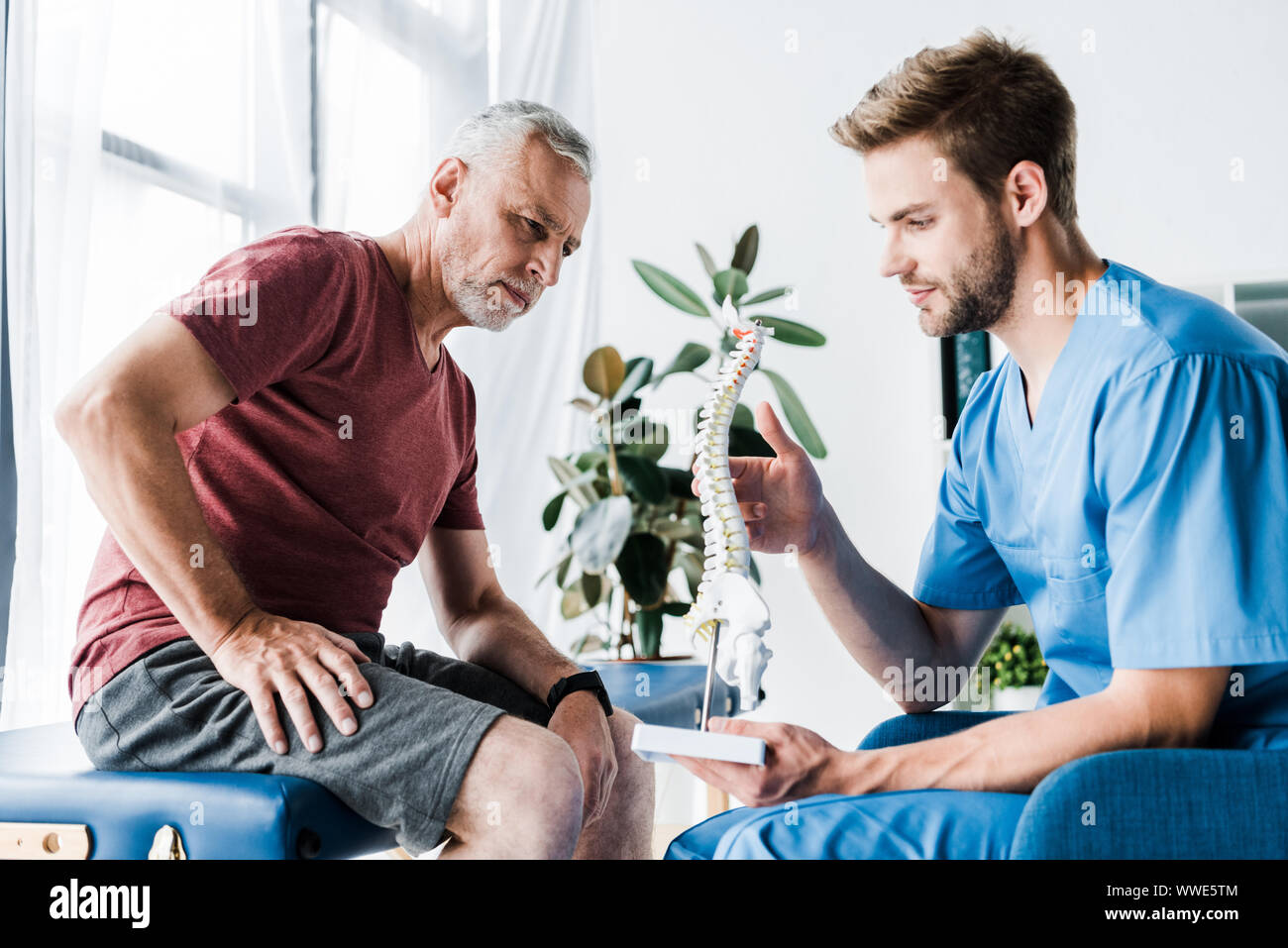 bearded patient looking at spine model near handsome doctor Stock Photo ...