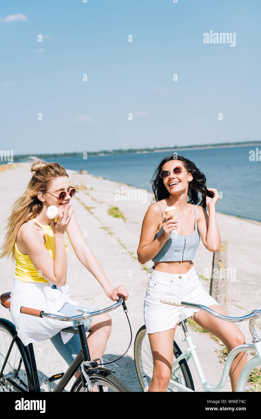 happy girls riding bikes with ice cream near river in summer Stock ...