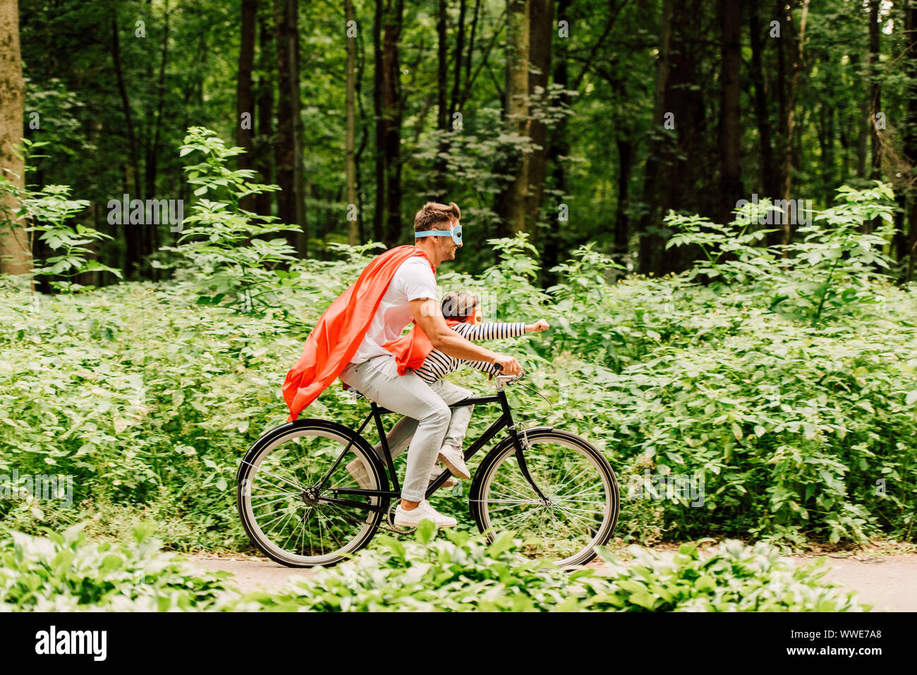 side view of father and kid riding bicycle while boy looking forward ...