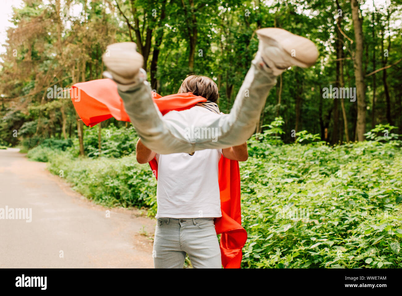 back view of man spinning around boy in red cloak Stock Photo - Alamy