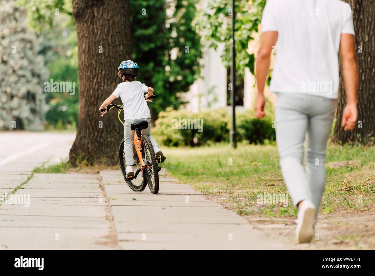 back view of kid riding bicycle while father walking after son Stock ...