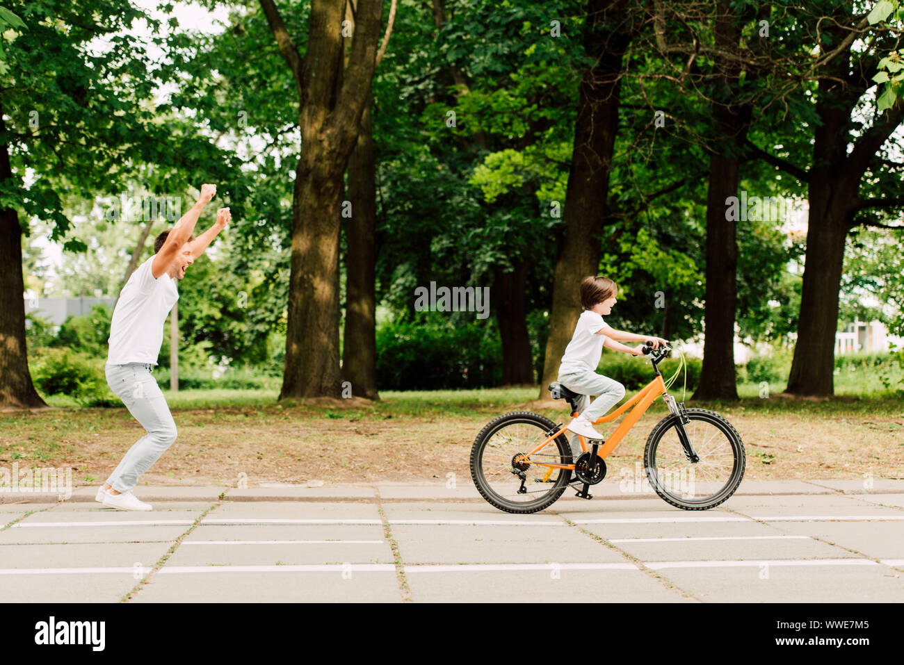 side view of happy father cheering son while kid riding bicycle Stock ...