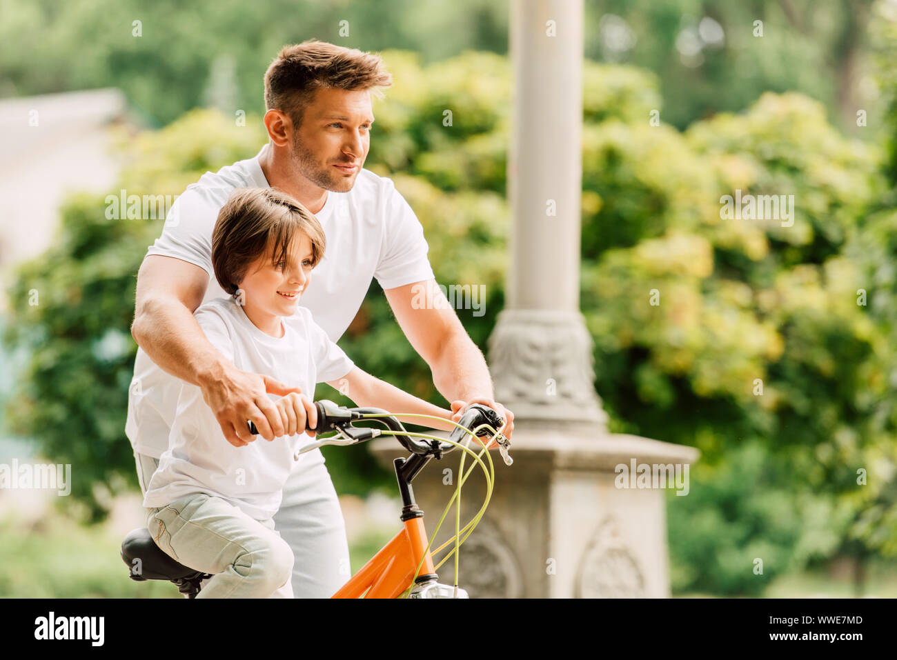 selective focus of father and son looking forward while kid riding ...