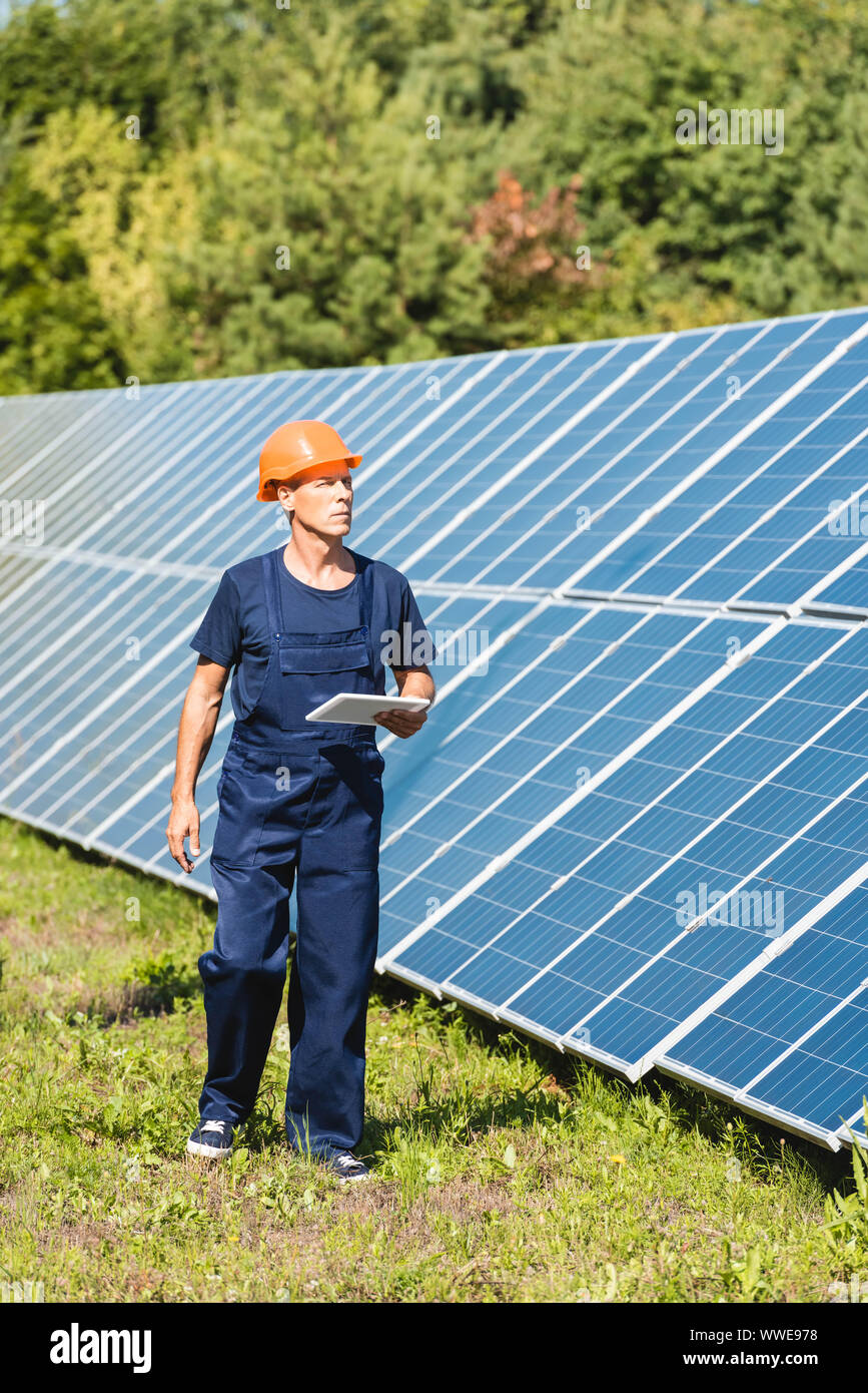 handsome engineer in overalls and hardhat holding digital tablet Stock ...