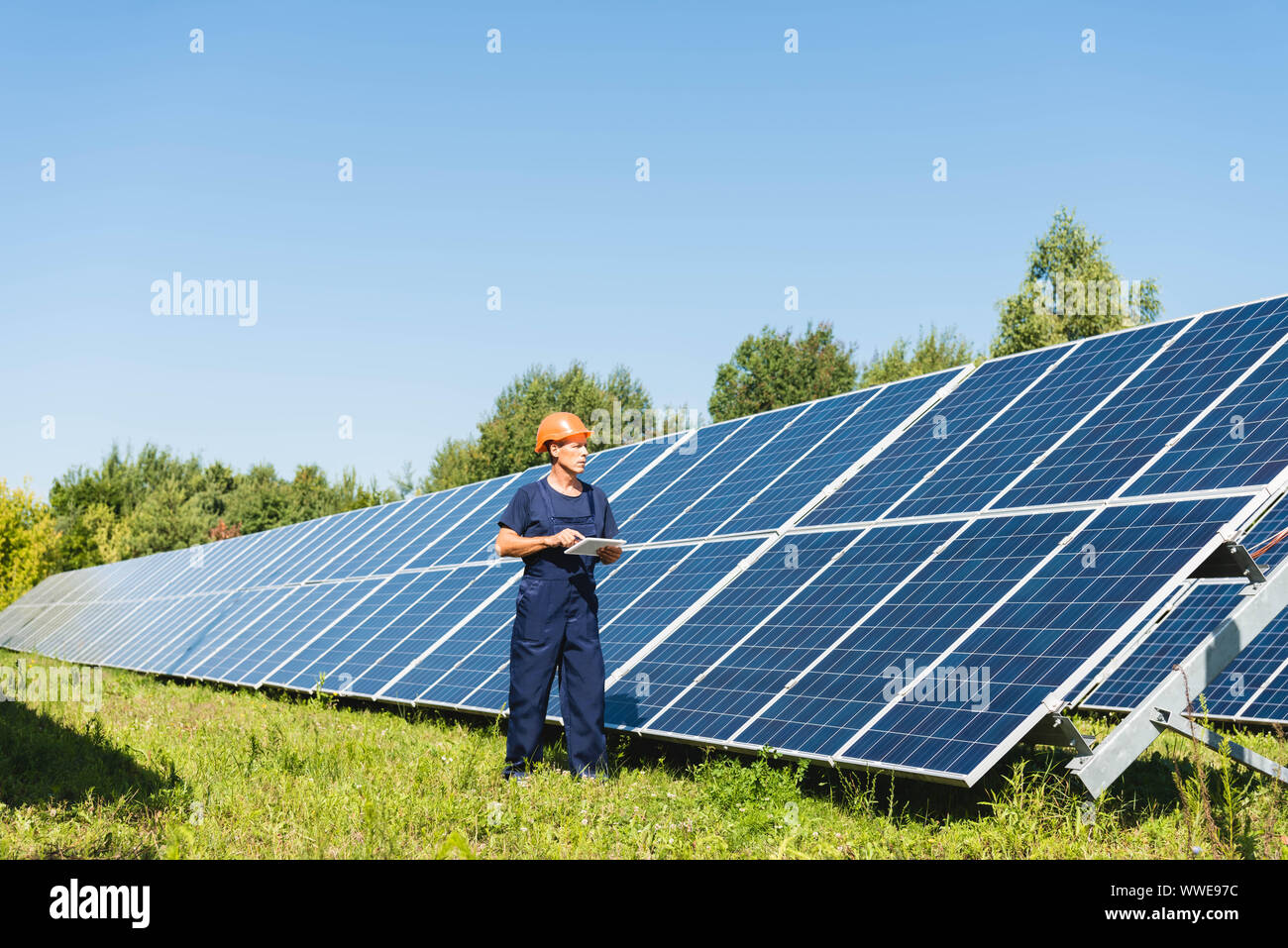 handsome engineer in overalls and hardhat holding digital tablet Stock ...