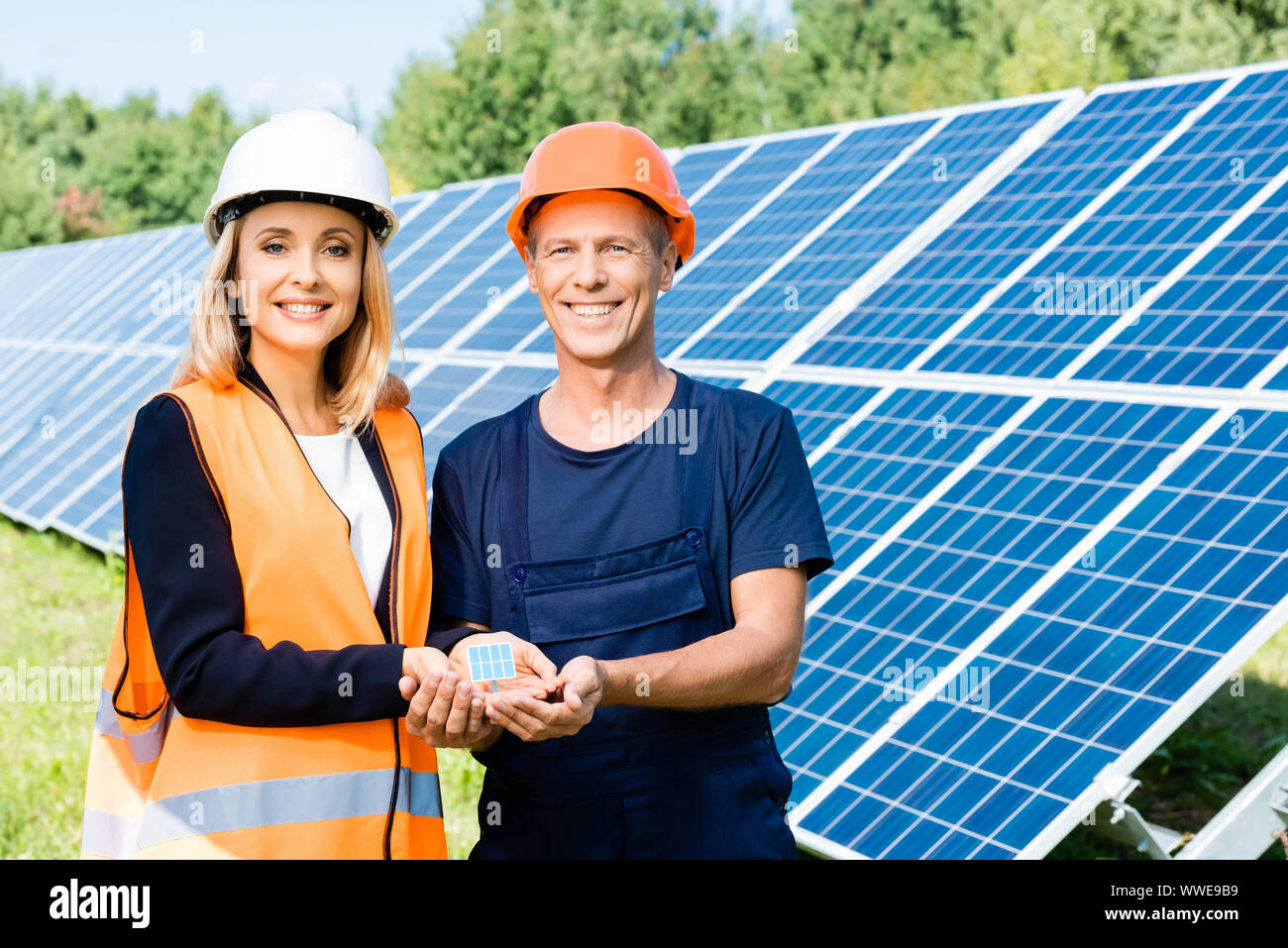 handsome engineer and businesswoman smiling and holding solar energy ...