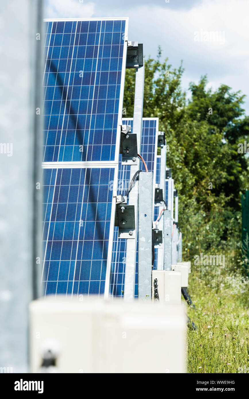 selective focus of blue solar energy batteries and green trees Stock ...