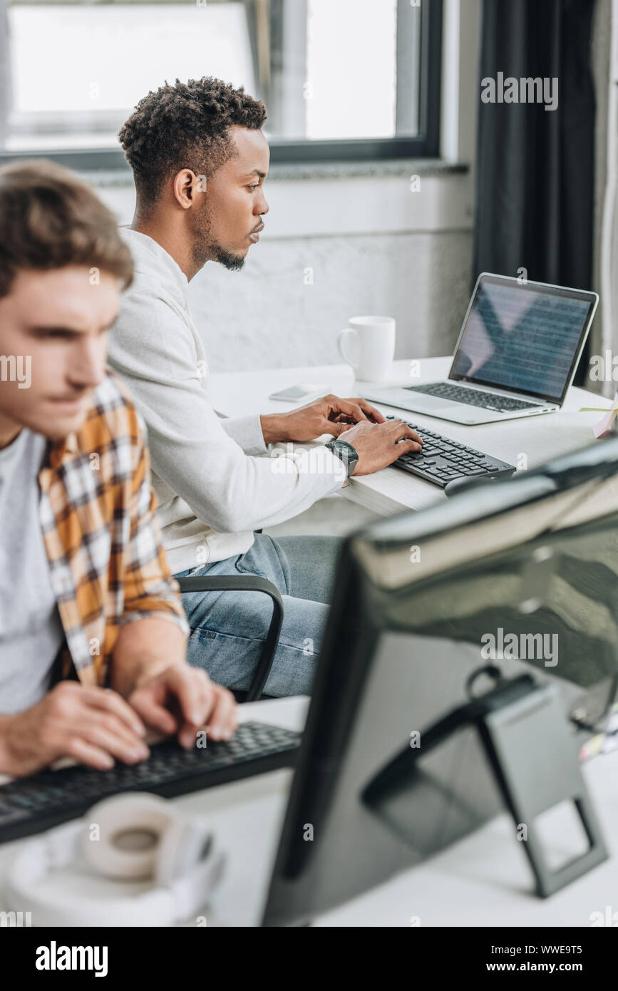 selective focus of two young multicultural programmers working together ...