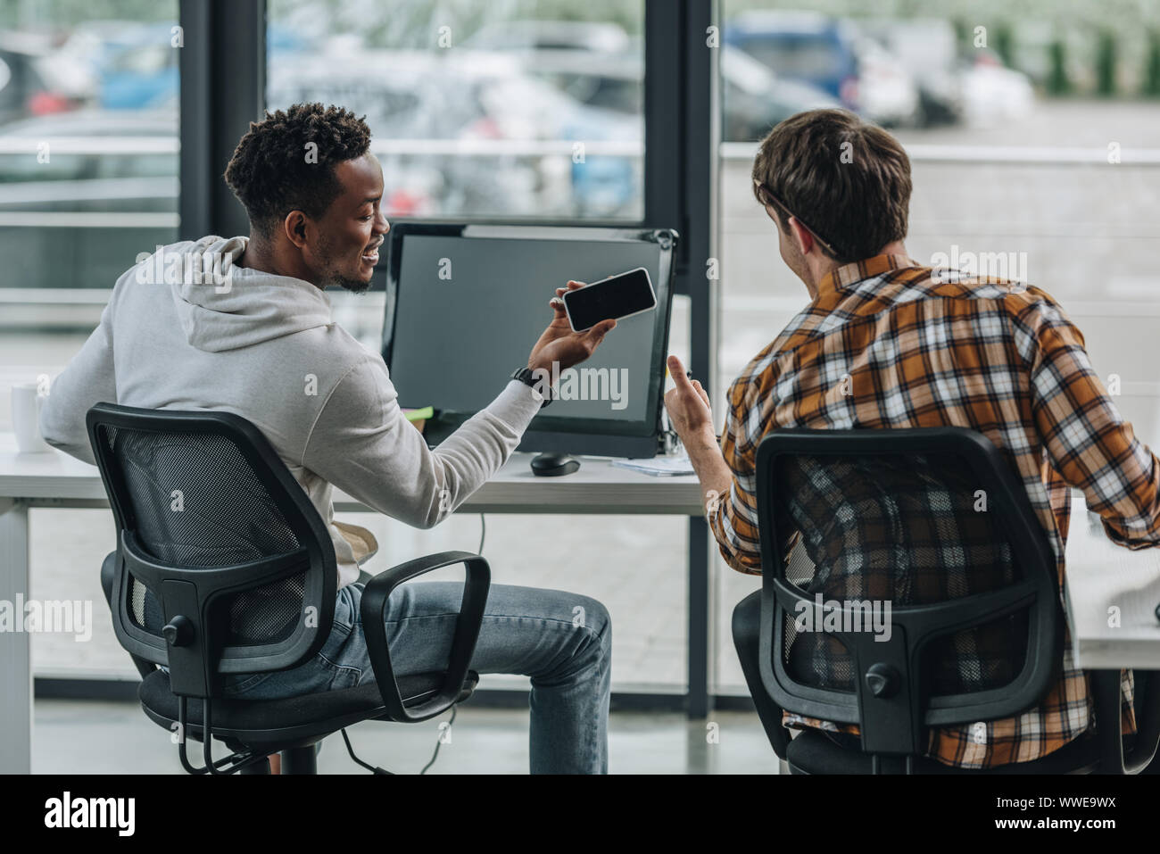 back view of young programmer showing thumb up near african american ...