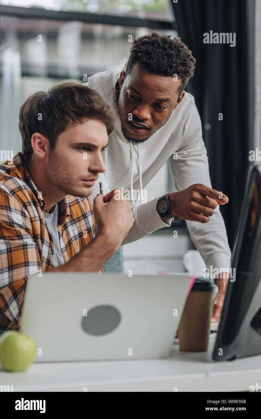 serious african american programmer pointing at computer monitor near ...