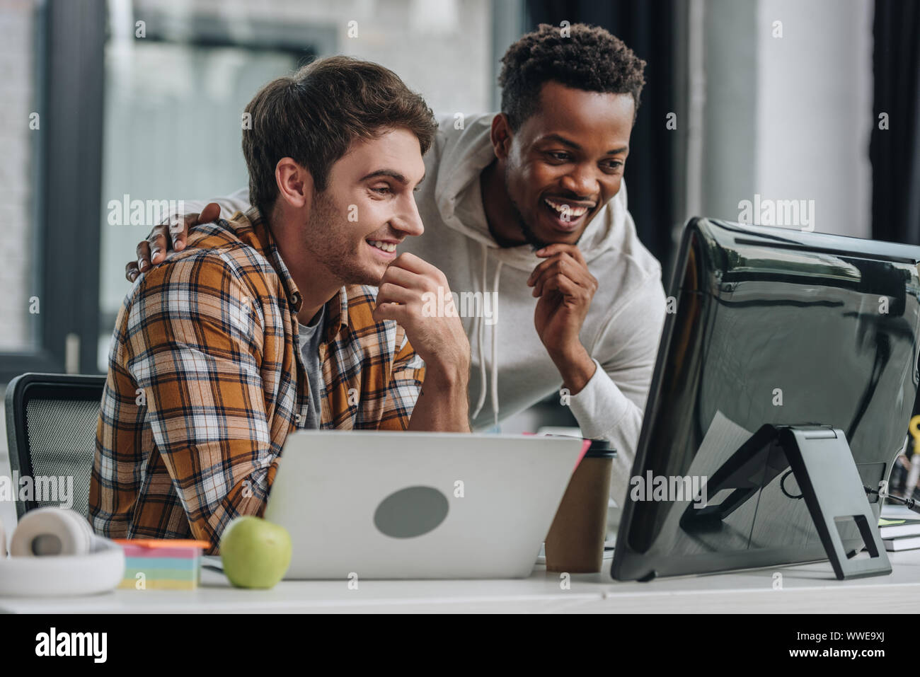 two cheerful multicultural programmers looking at computer monitor ... two cheerful multicultural programmers looking at computer monitor ...