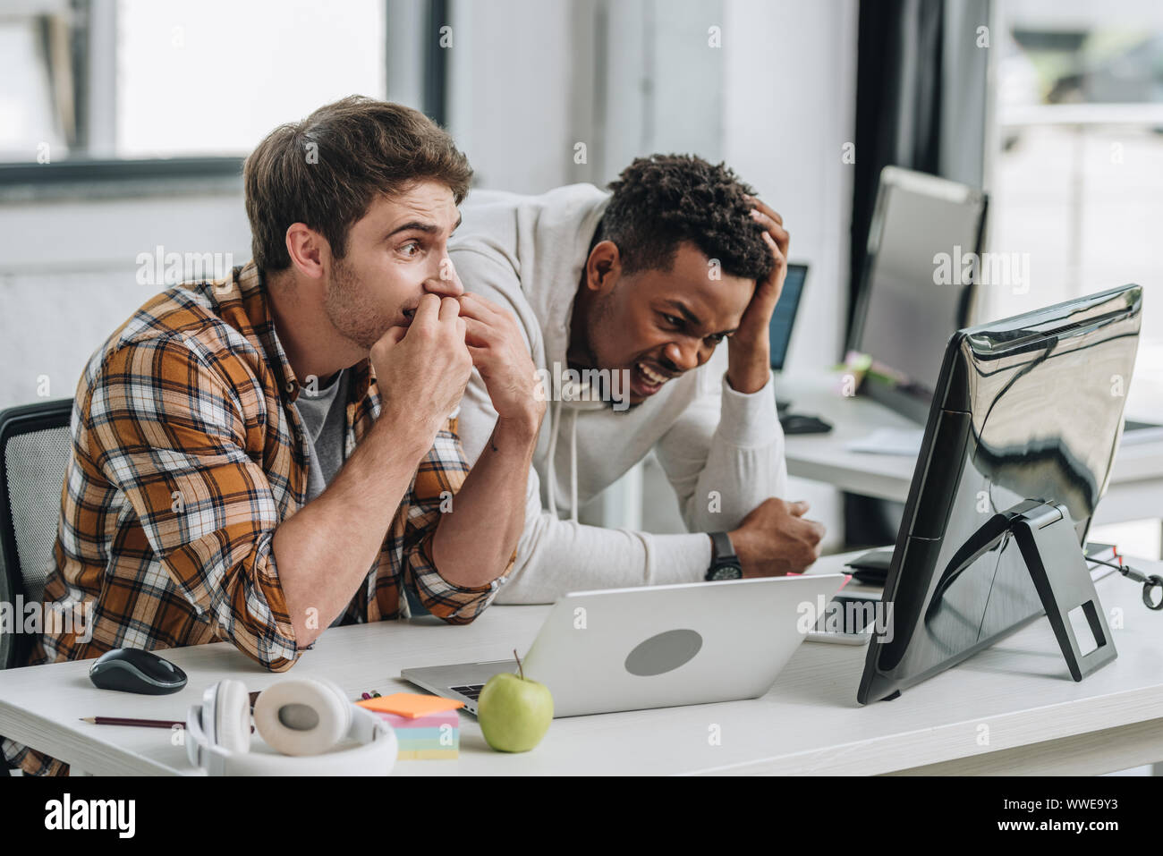 two shocked multicultural programmers looking at laptop in office Stock ...