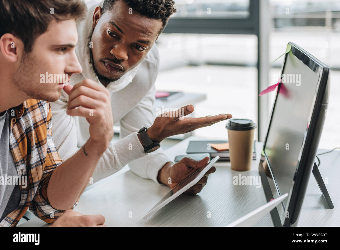 serious african american programmer pointing at computer monitor near ...