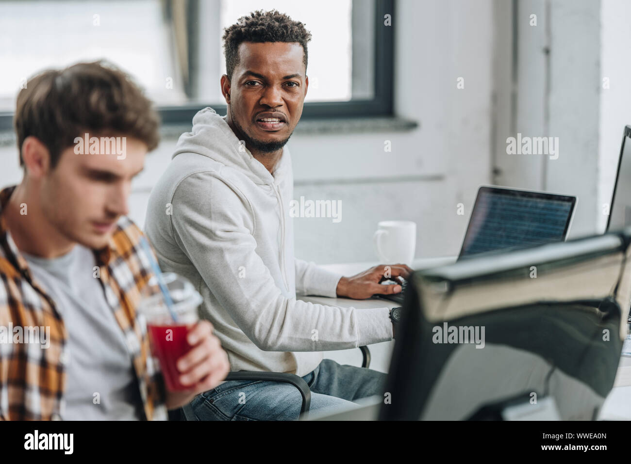 selective focus of angry african american programmer sitting near ...