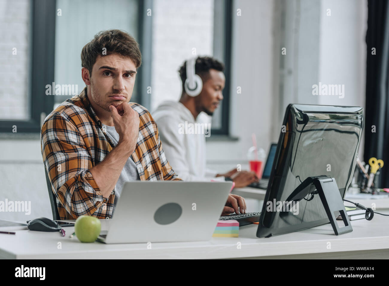 Selective Focus Of Upset Programmer Looking At Camera While Sitting