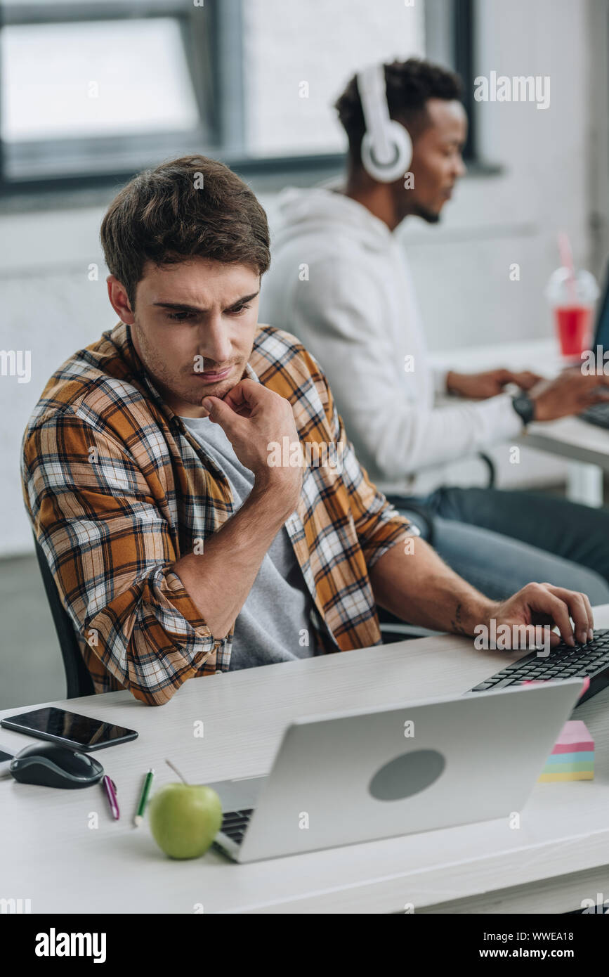 selective focus of thoughtful programmer working near african american ...