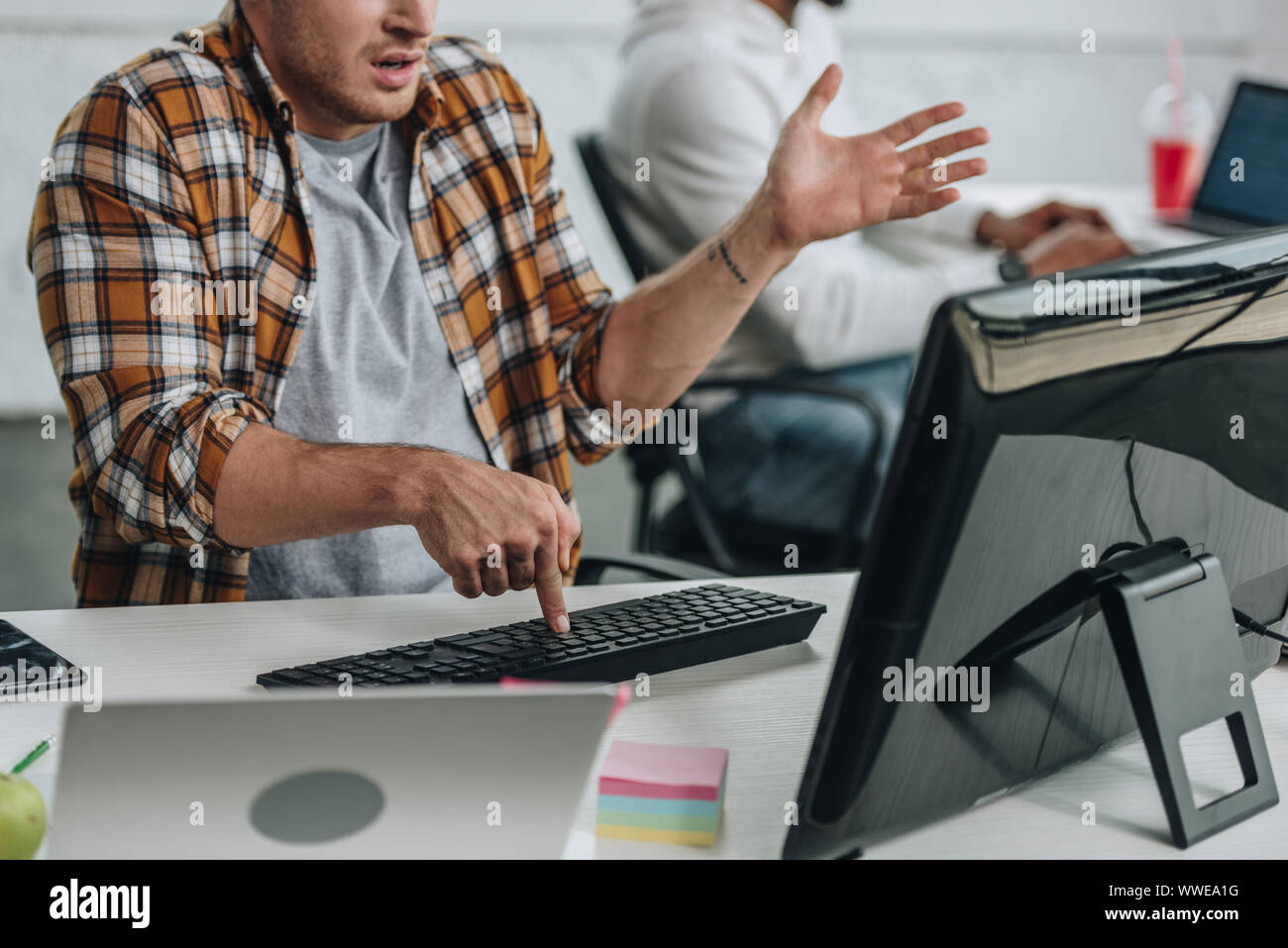 cropped view of programmer gesturing while using computer near african ...