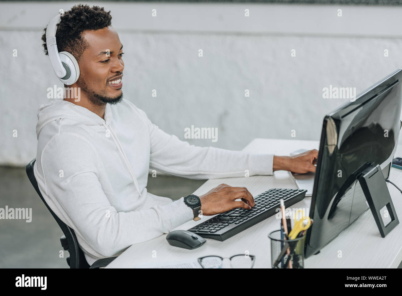 happy african american programmer sitting at workplace in headphones ...