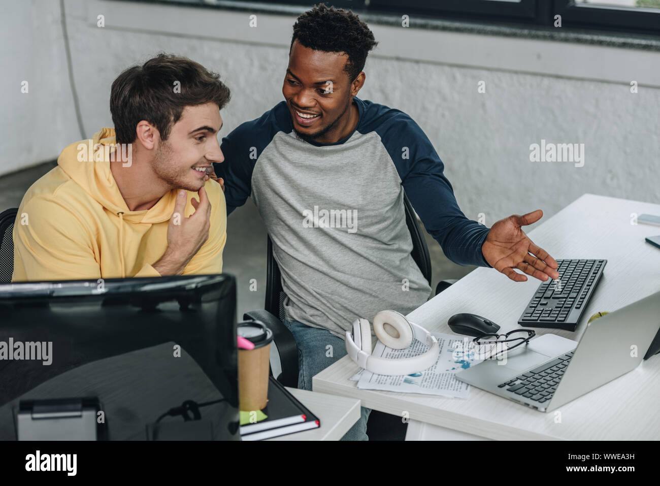 cheerful african american programmer pointing at computer monitor while ...