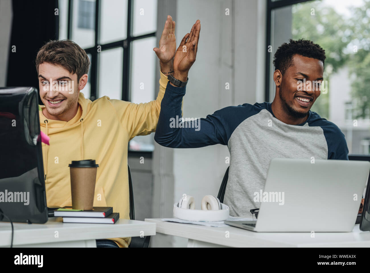 happy multicultural programmers giving high five while working in ...