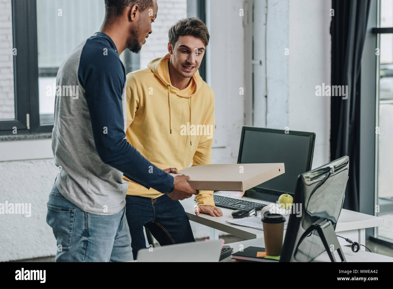 young african american programmer holding pizza box while standing near ...