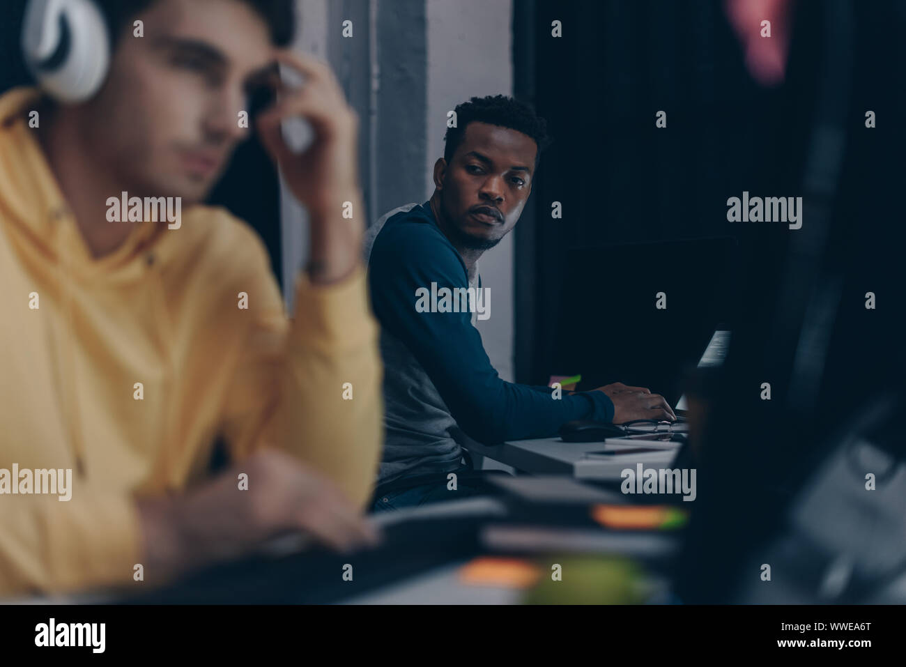 selective focus of african american programmer looking at colleague in ...