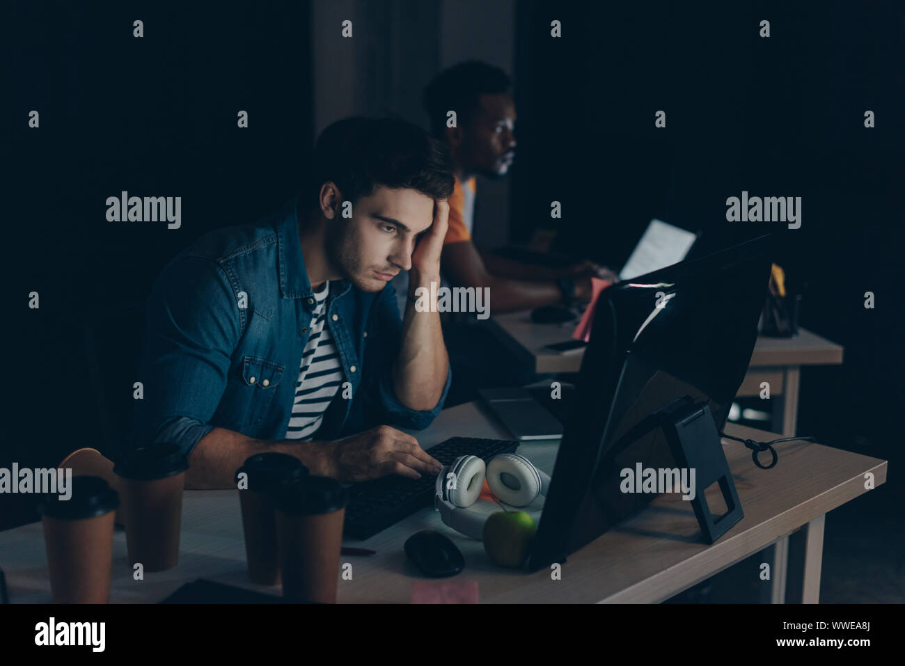 selective focus of thoughtful programmer working at night in office ...