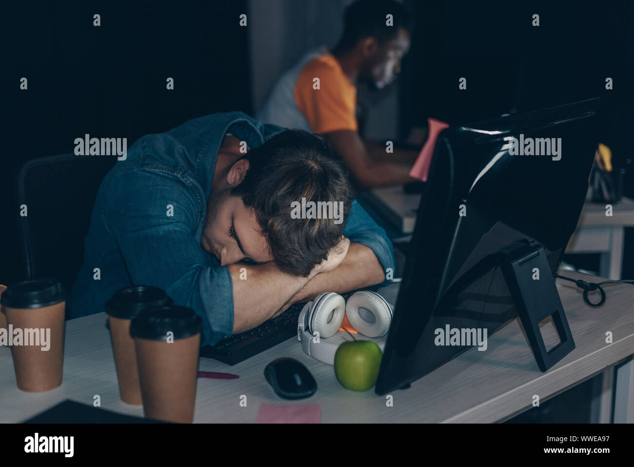 selective focus of tired programmer sleeping at workplace near african ...