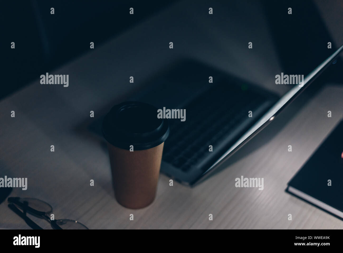 desk with laptop and coffee to go at night in office Stock Photo - Alamy