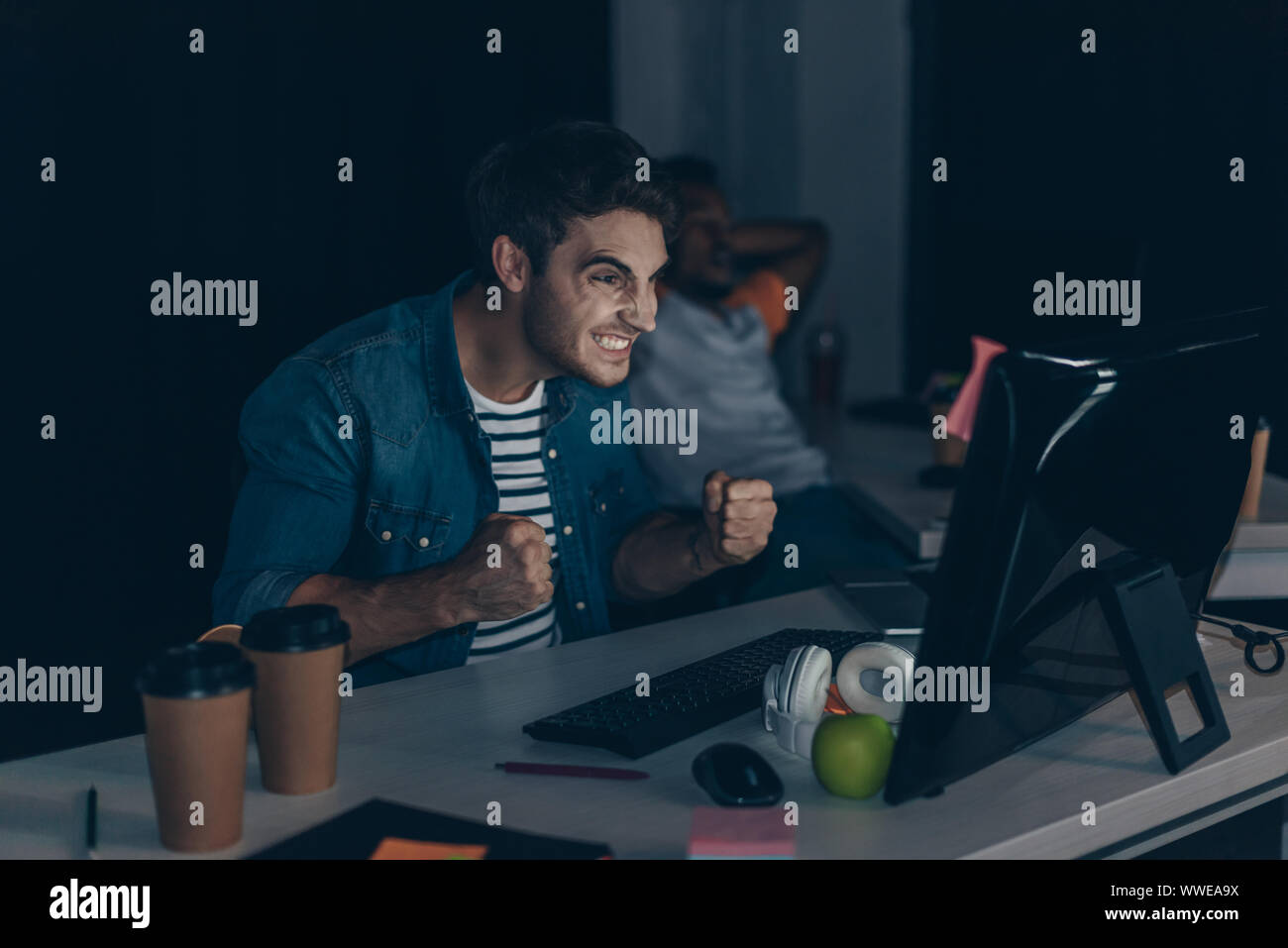 angry programmer gesturing while working at night in office near ...