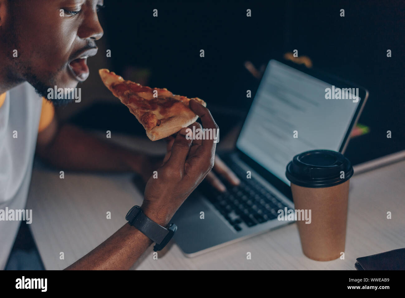 young african american programmer eating pizza while sitting at ...