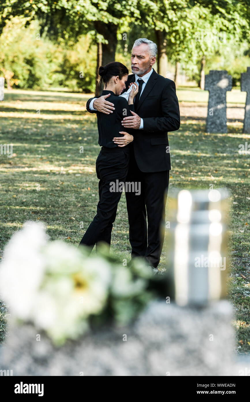 selective focus of senior man hugging upset woman in cemetery Stock ...