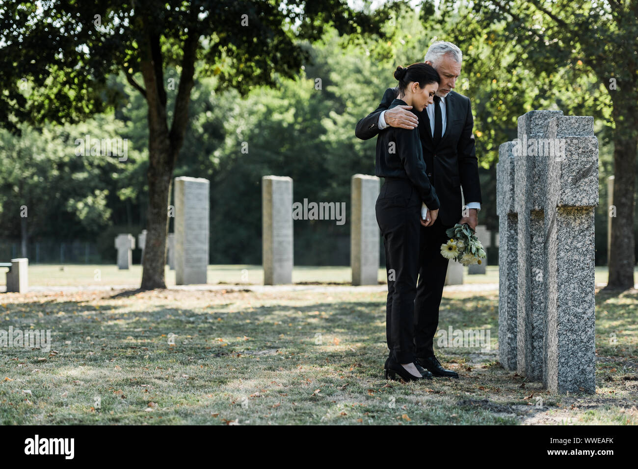 upset man hugging frustrated woman in cemetery Stock Photo - Alamy