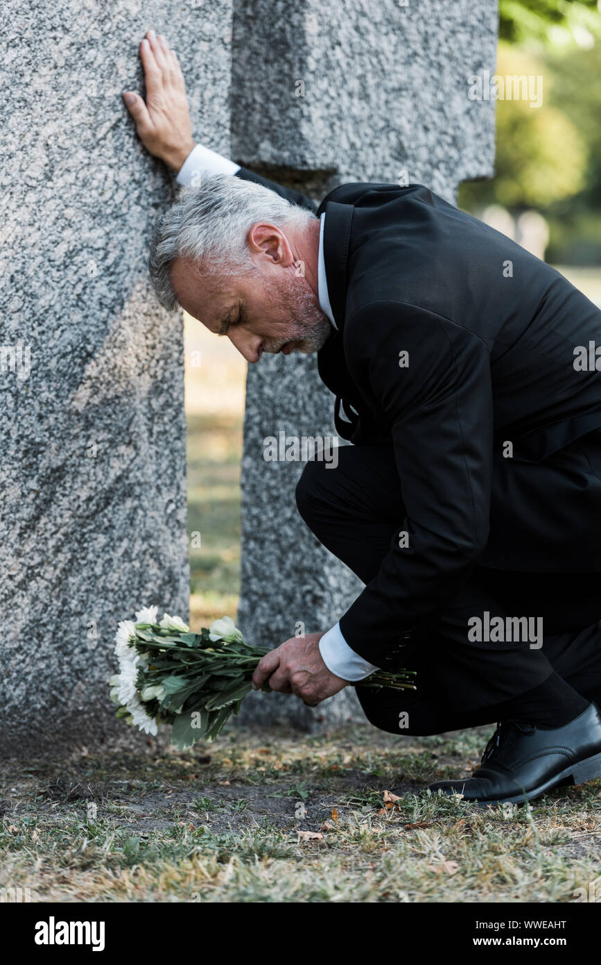 sad man with grey hair putting flowers on graveyard Stock Photo - Alamy