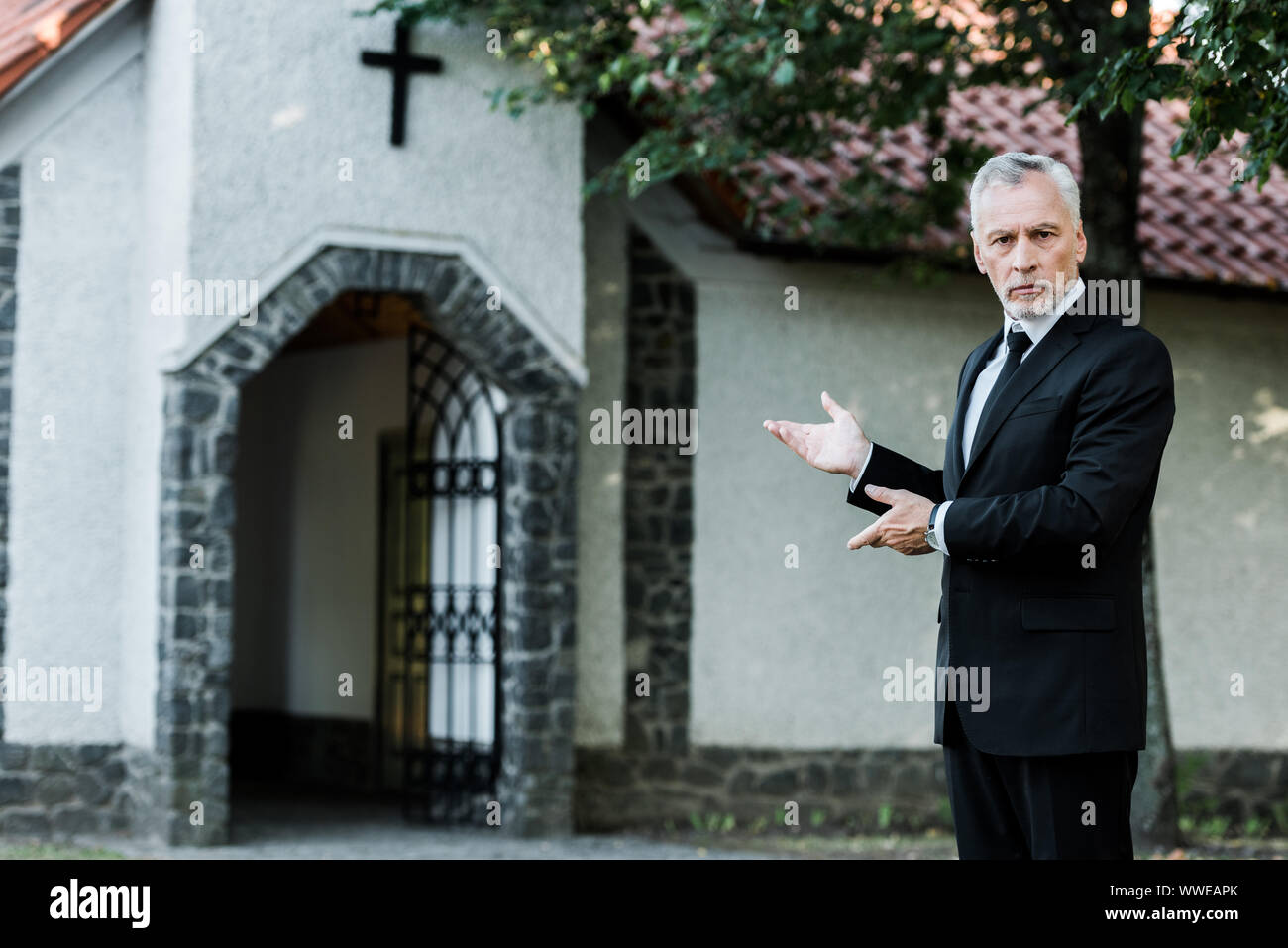 handsome senior man in suit gesturing near church Stock Photo - Alamy