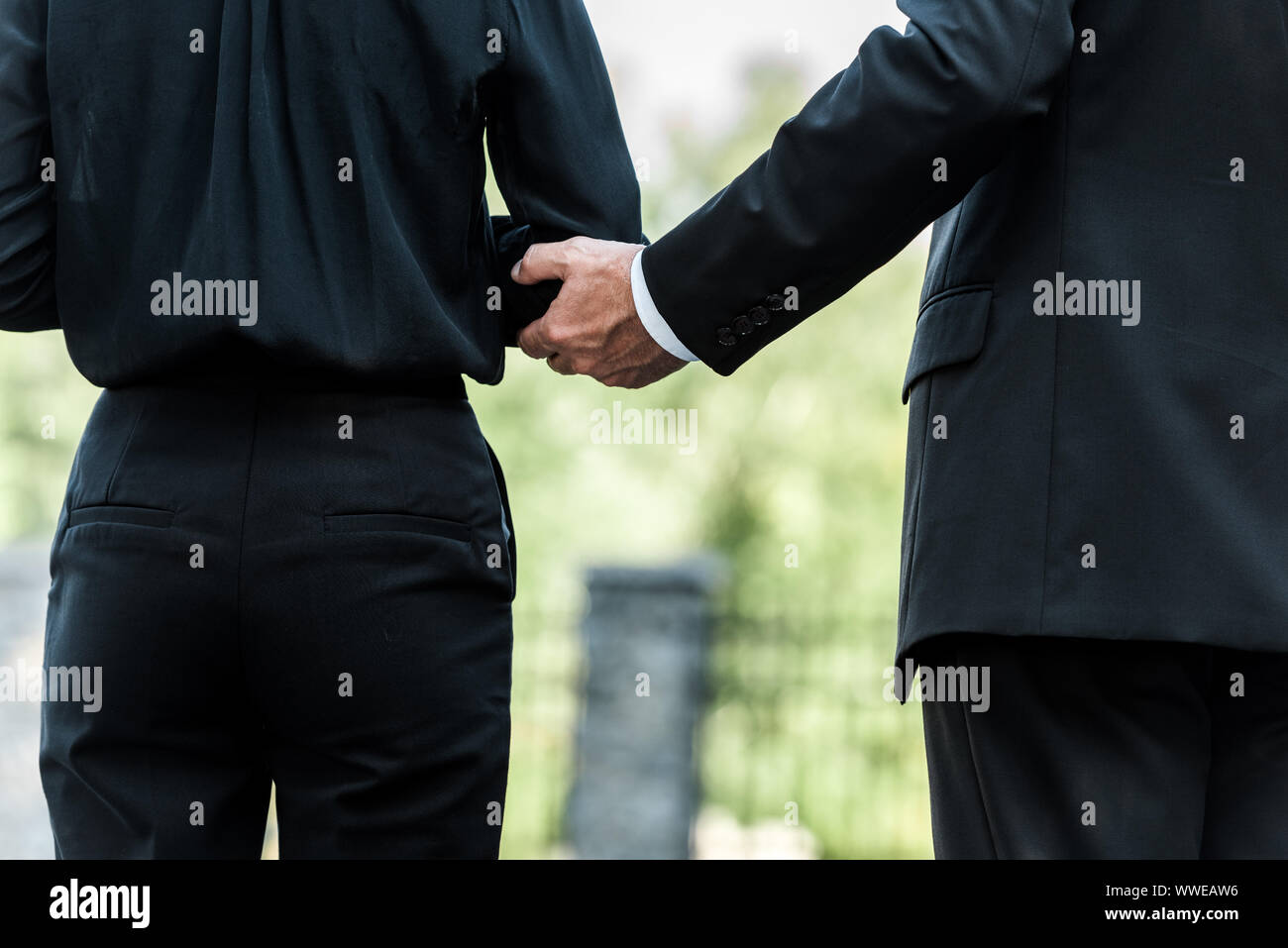 cropped view of man touching hand on woman standing on funeral Stock ...