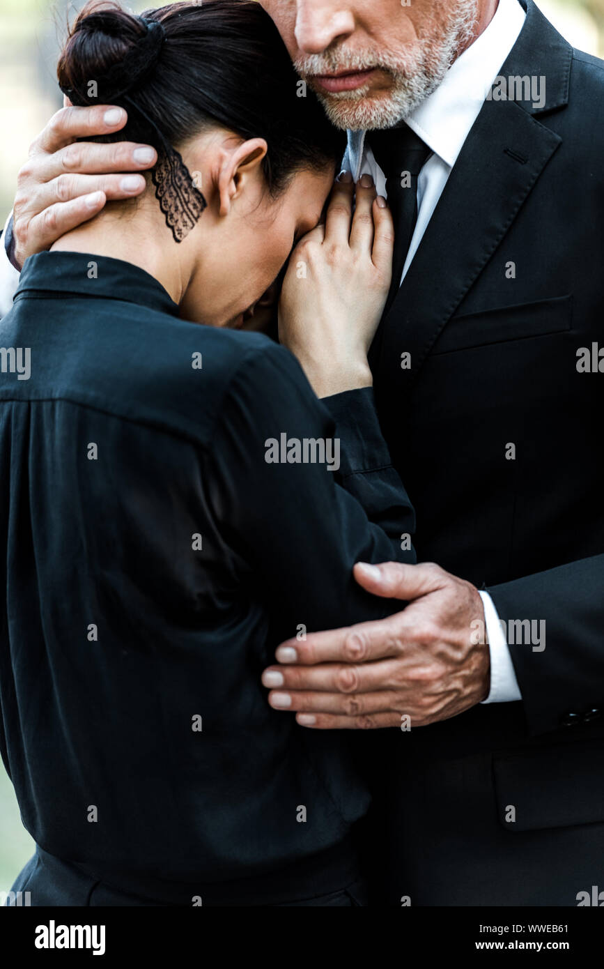 cropped view of upset senior man hugging woman on funeral Stock Photo ...