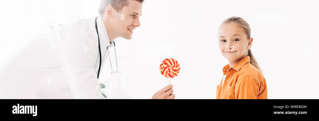 panoramic shot of pediatrist giving candy to child on white Stock Photo ...