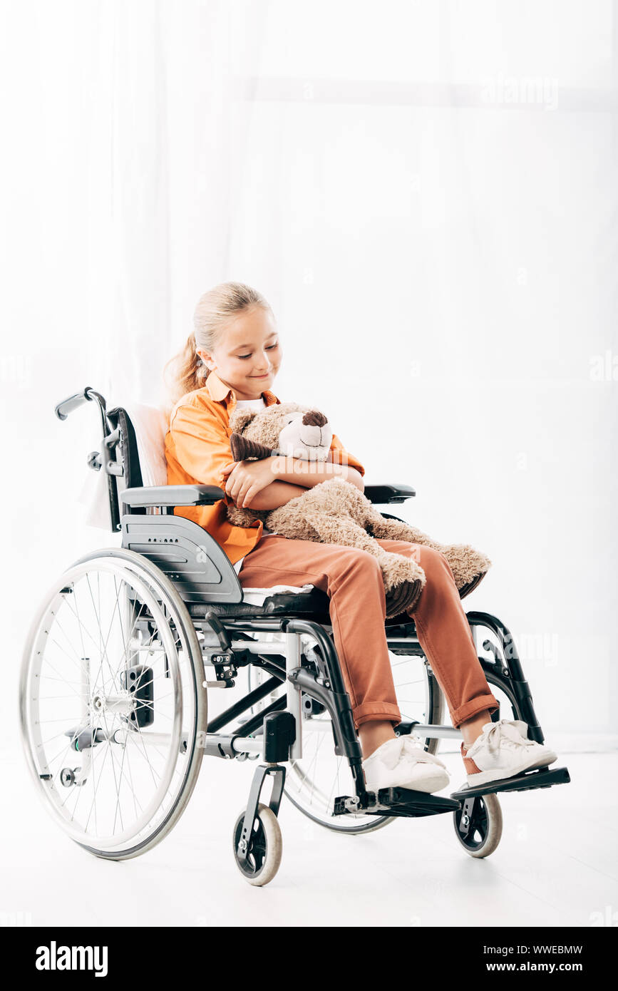 smiling kid holding teddy bear and sitting on wheelchair Stock Photo ...