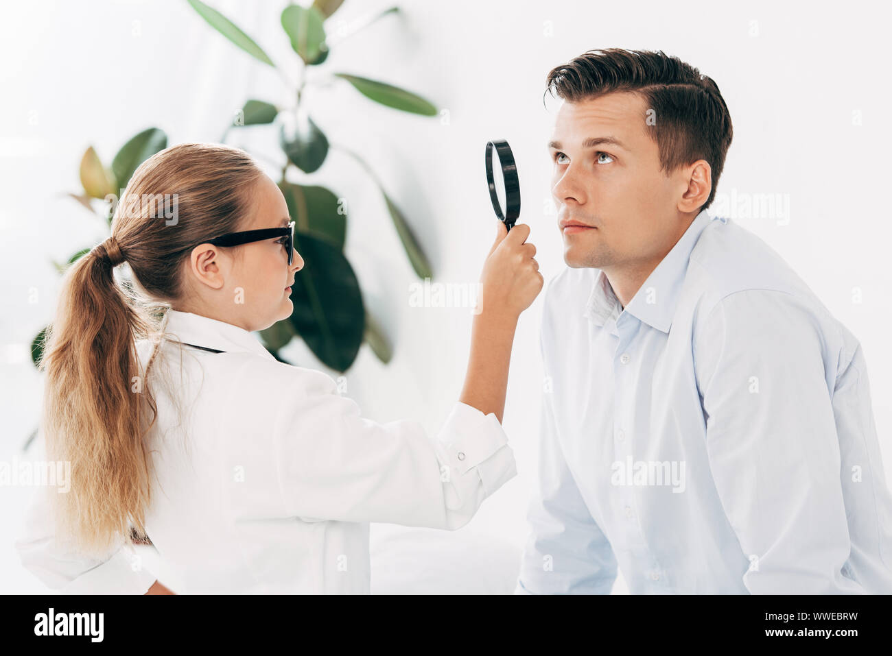 child in doctor costume examining patient with magnifier Stock Photo ...