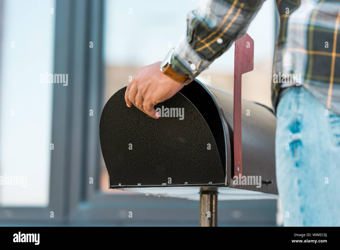 cropped view of man opening black mailbox Stock Photo - Alamy