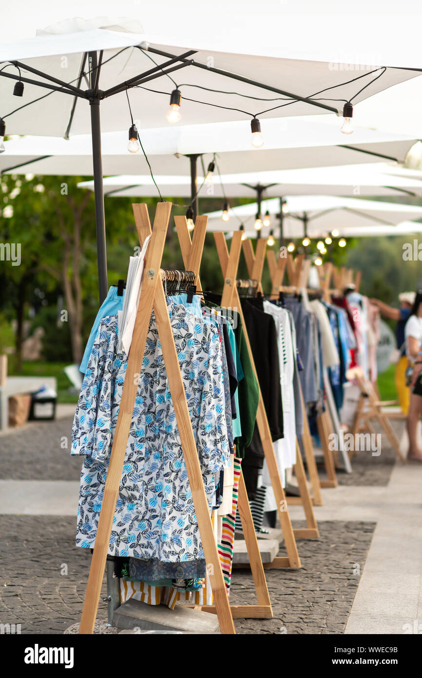 Racks with clothes outdoors. Designer sells clothes at a city fair ...