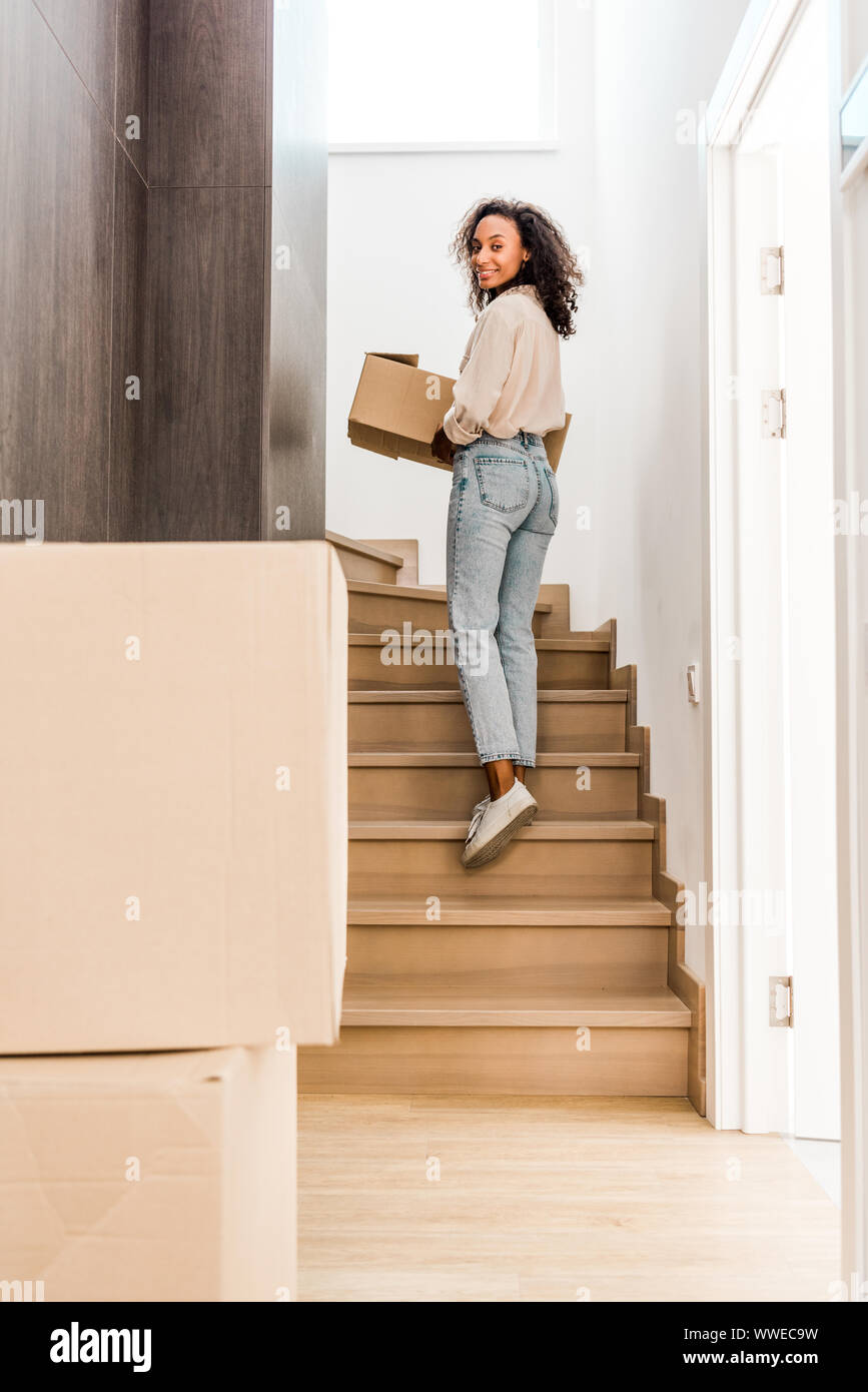 full length view of beautiful african american woman walking upstairs ...