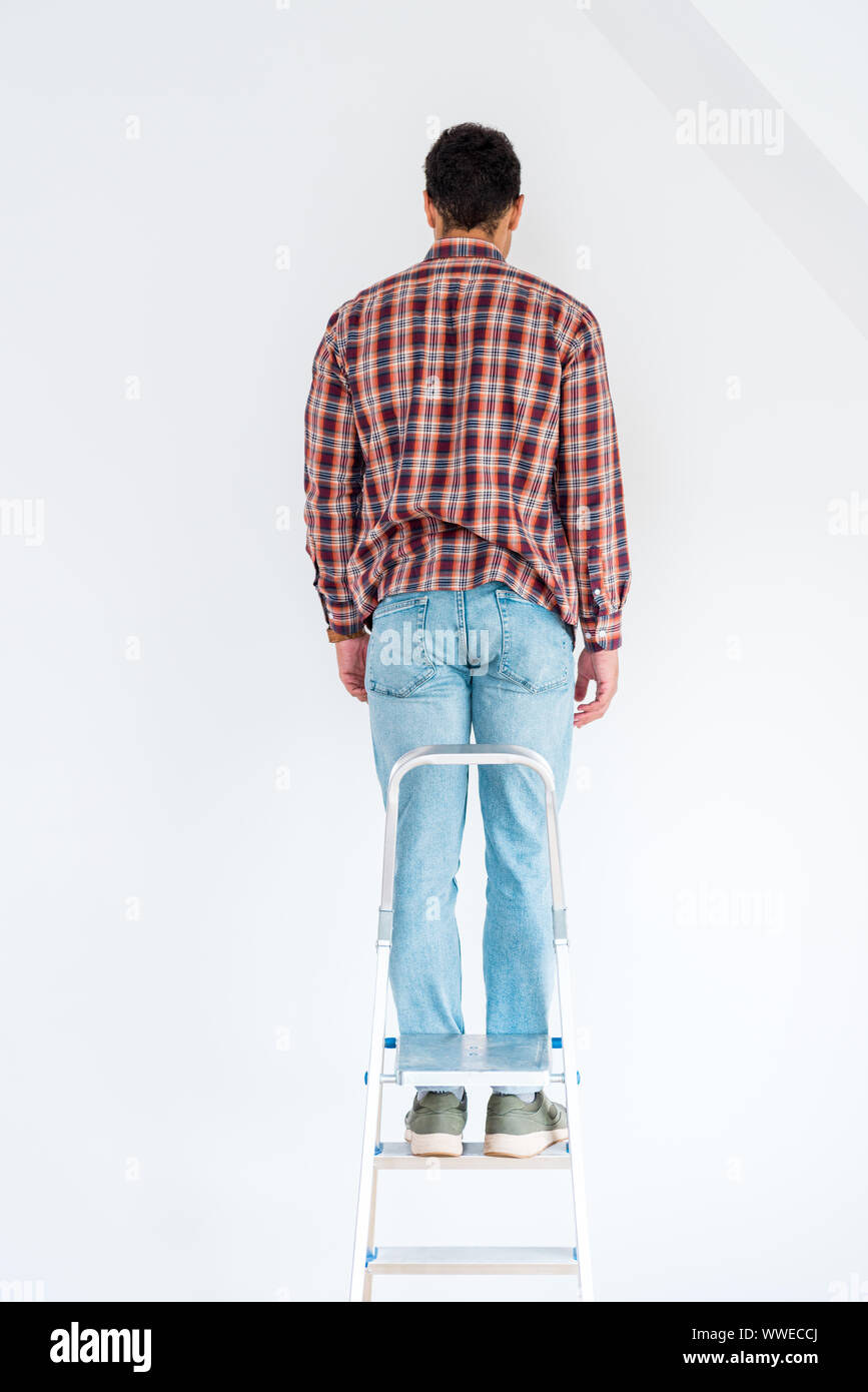 back view of man standing at ladder and looking at wall isolated on ...