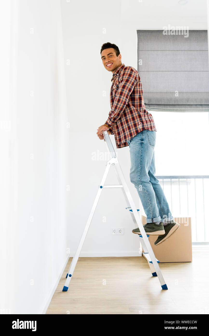 full length view of african american man standing at ladder and looking ...