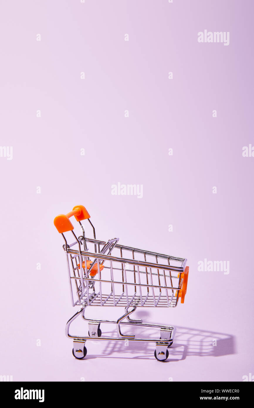 small decorative shopping cart on violet background Stock Photo - Alamy