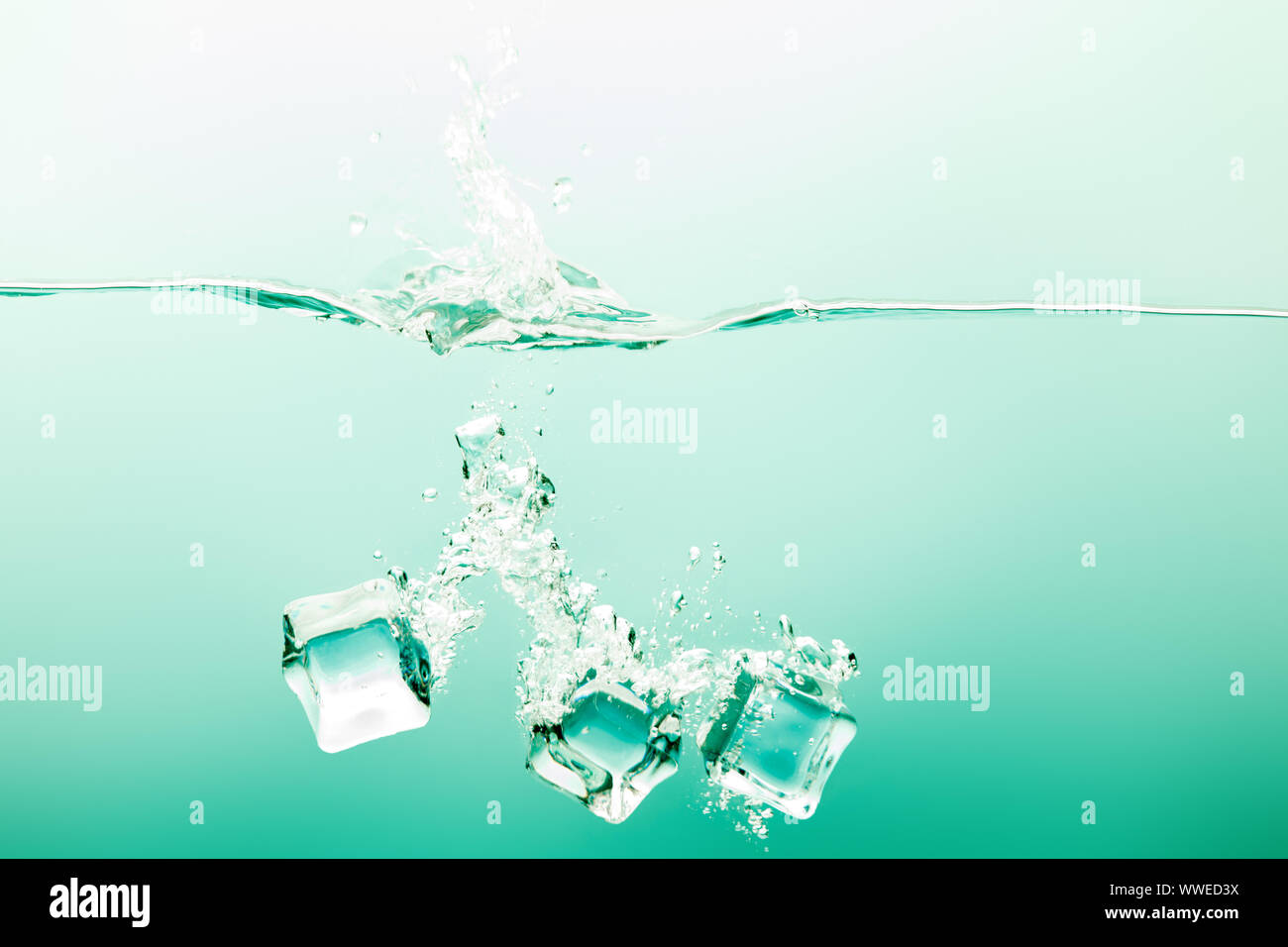transparent pure water with splash, ice cubes and bubbles on green ...
