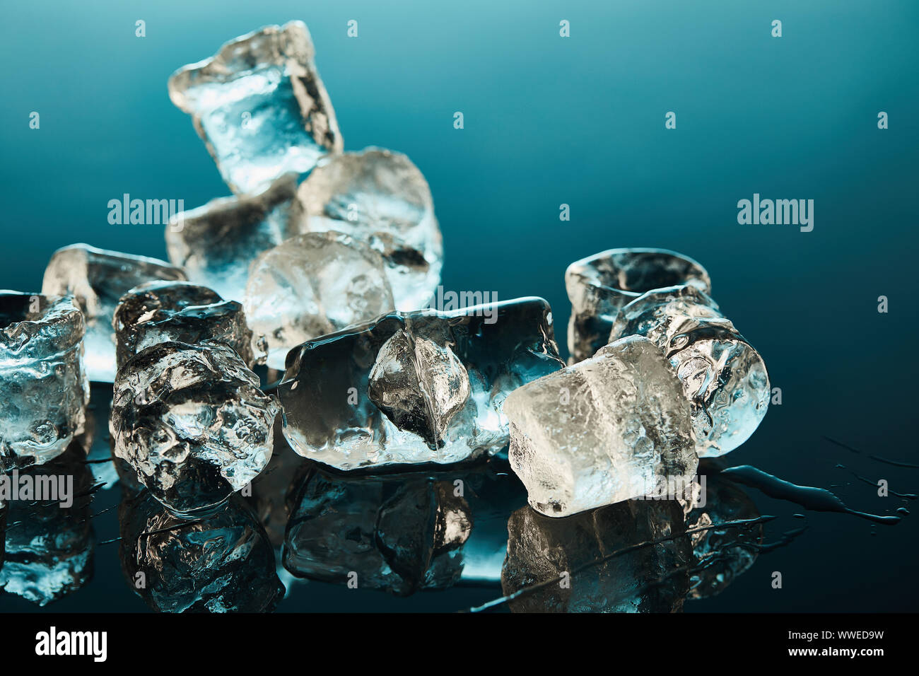 stack of transparent melting ice cubes on emerald background Stock ...